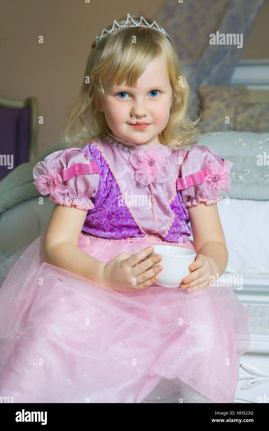 Little happy princess girl in pink dress and crown in her royal room ...
