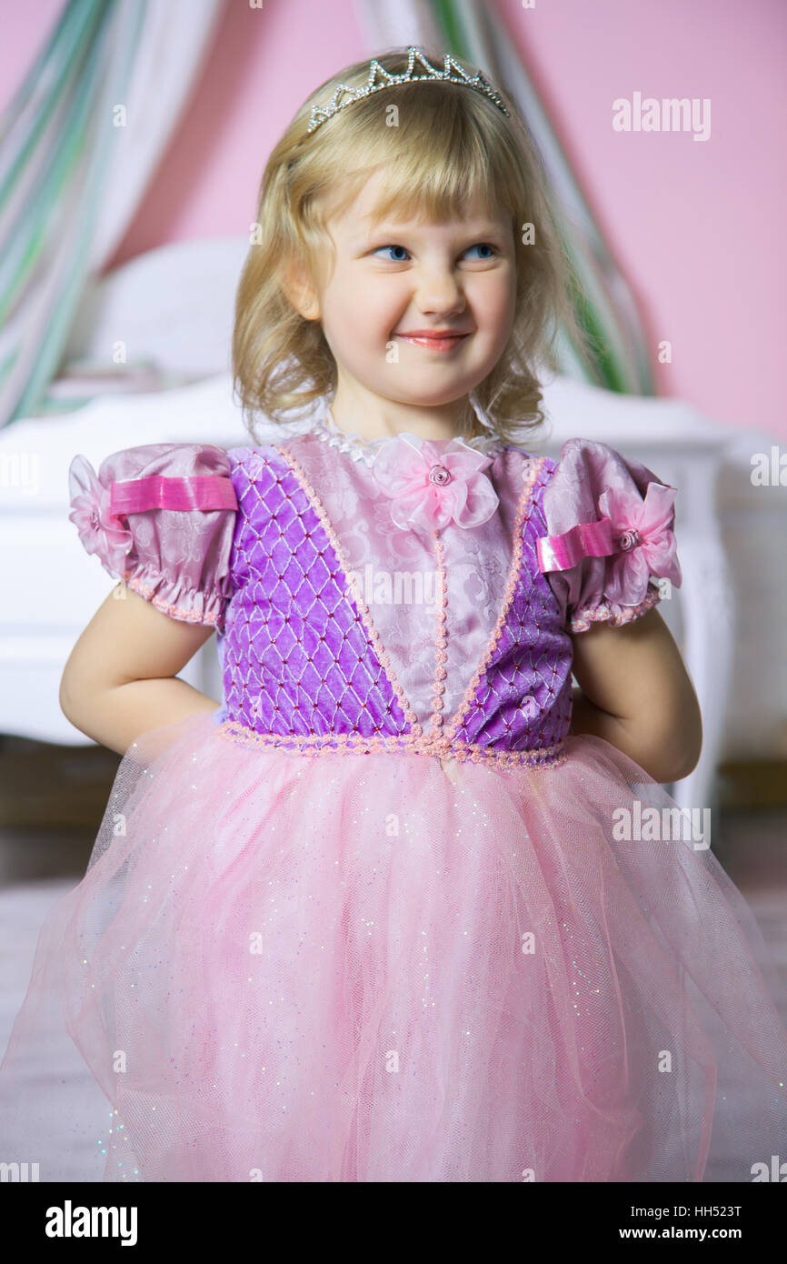 Little happy princess girl in pink dress and crown in her royal room ...