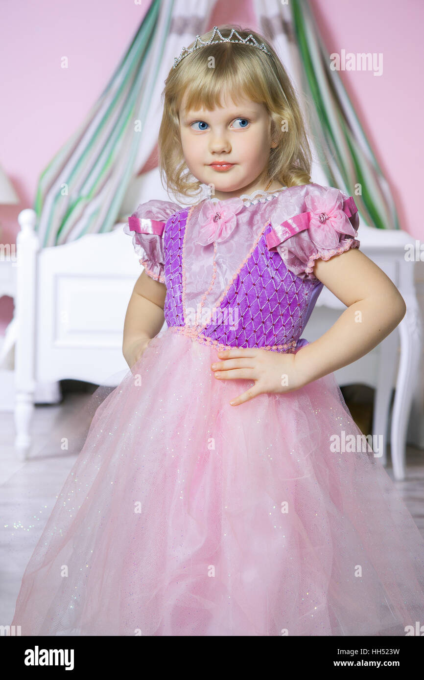 Little happy princess girl in pink dress and crown in her royal room ...