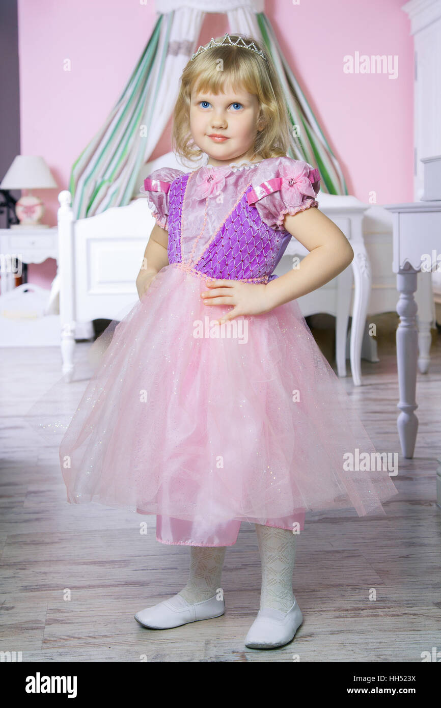 Little happy princess girl in pink dress and crown in her royal room ...
