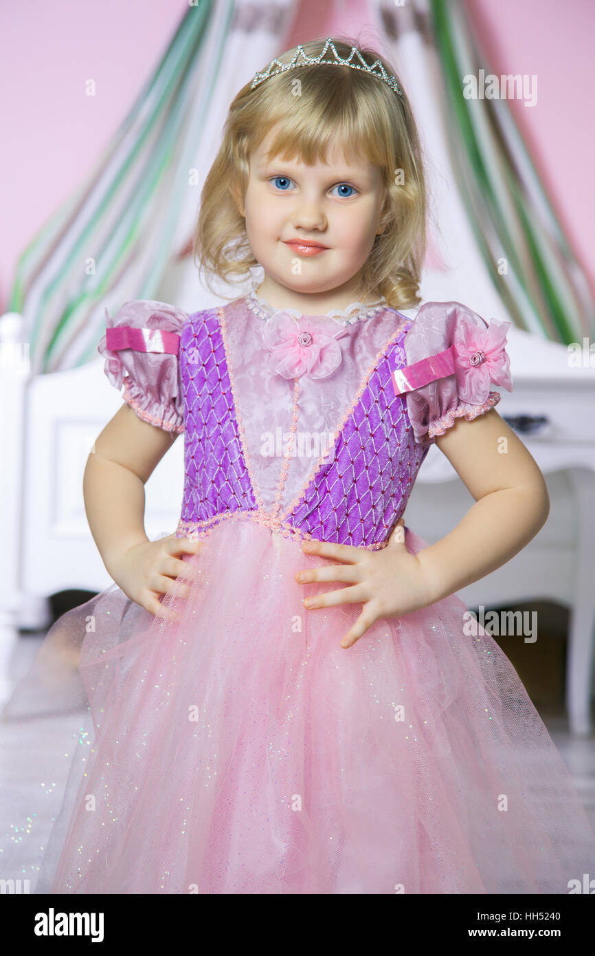 Little happy princess girl in pink dress and crown in her royal room ...