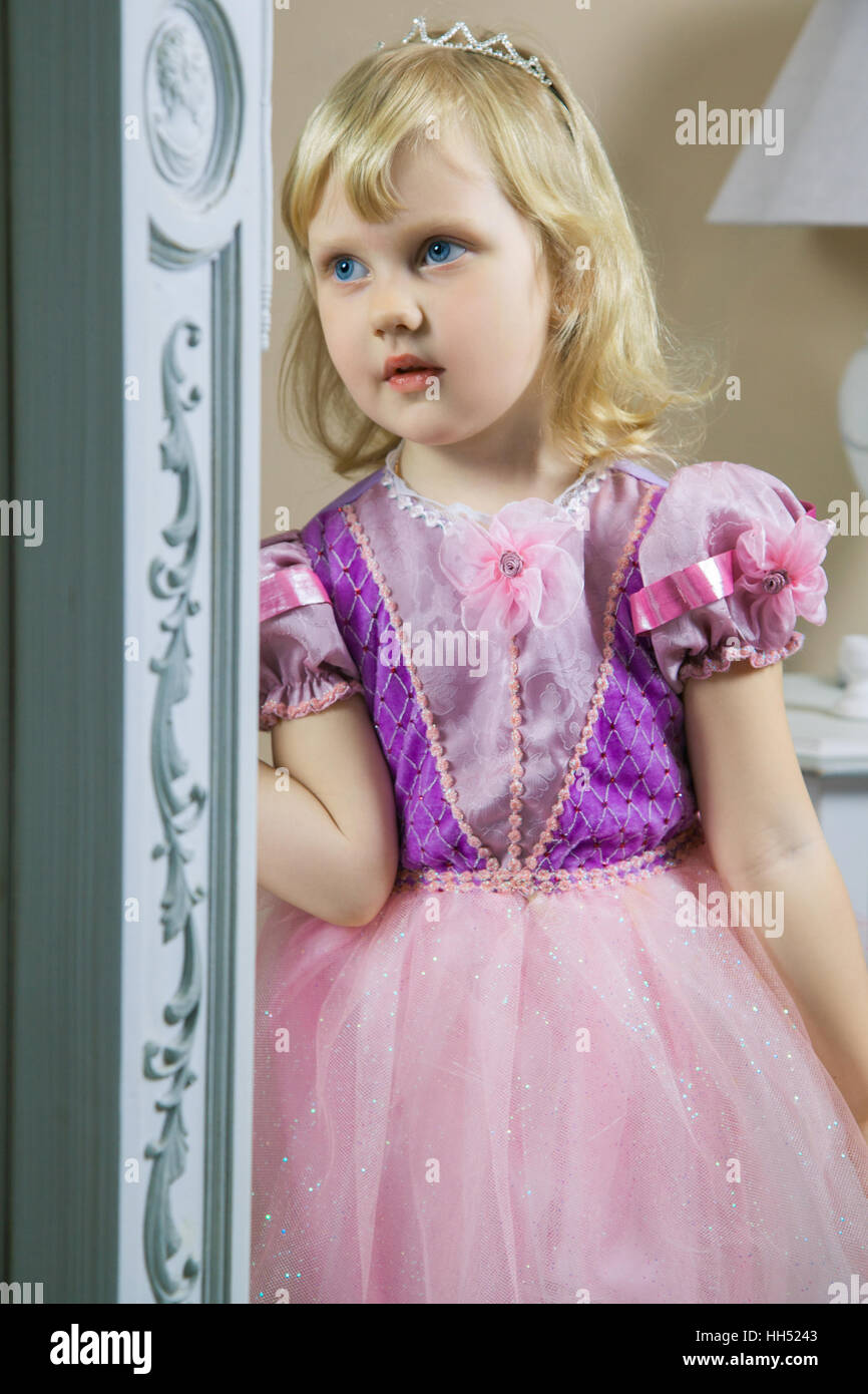 Little happy princess girl in pink dress and crown in her royal room ...