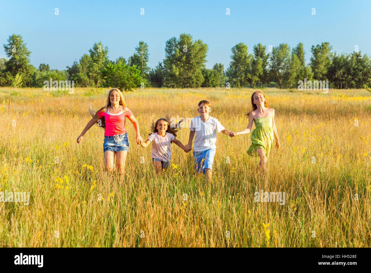 four happy beautiful children running playing moving together in the ...