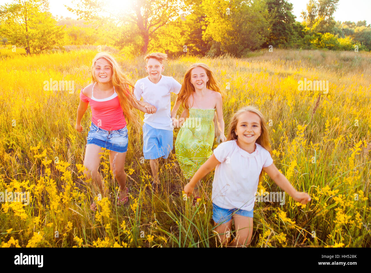 four happy beautiful children running playing moving together in the ...