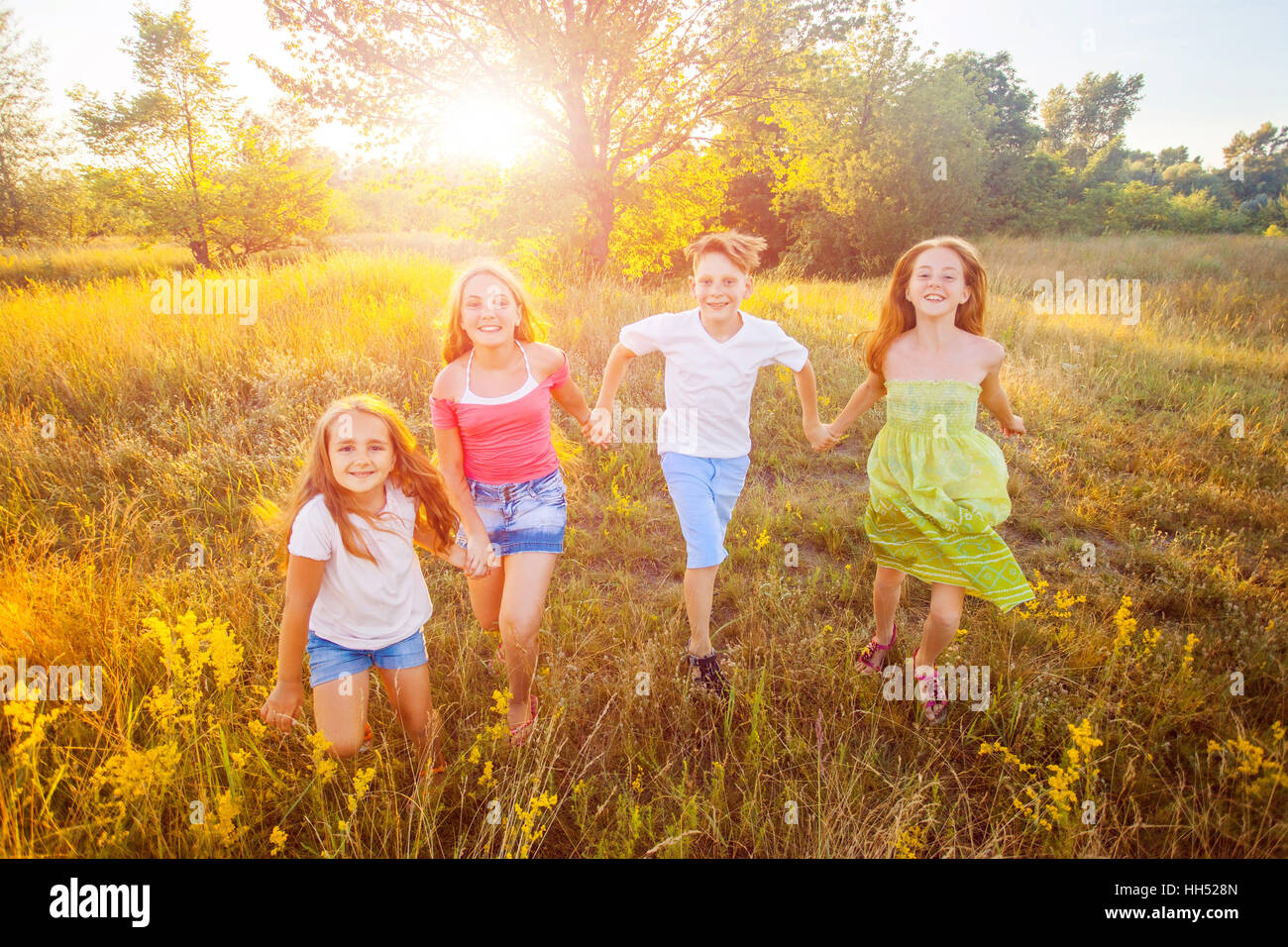 four happy beautiful children running playing moving together in the ...