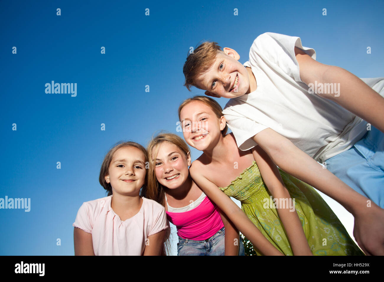 four happy beautiful children looking at camera from top in the sunny ...