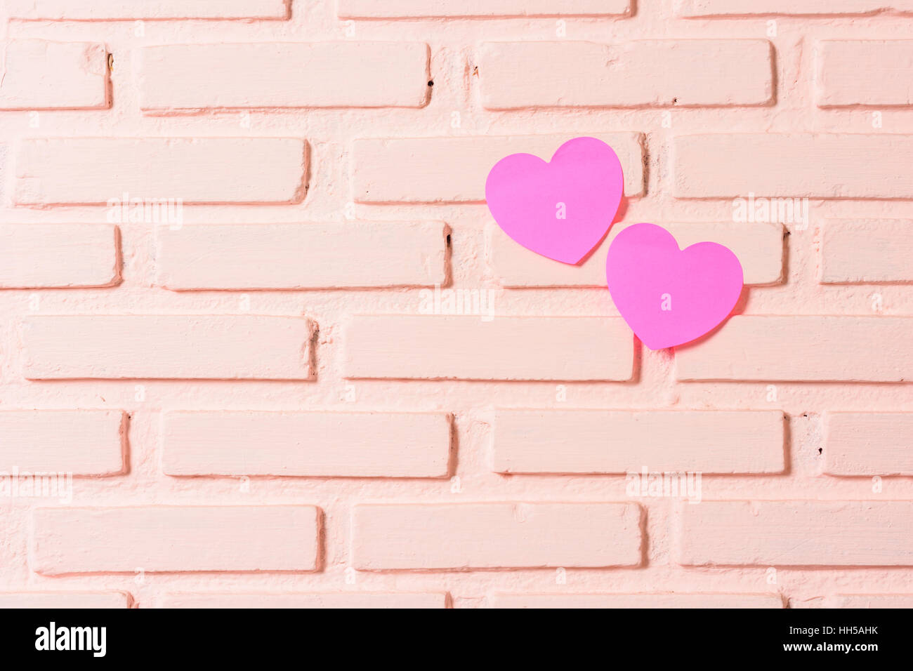 Pink sticky notes hearts shaped lined holes on the wall Stock Photo - Alamy