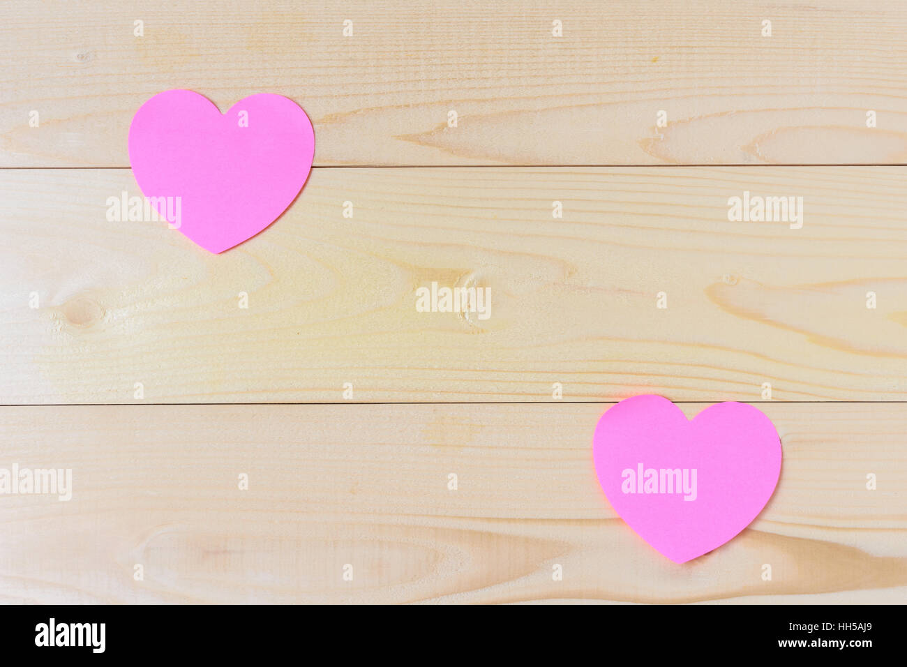 Pink sticky notes hearts shaped holes on wooden background with copy ...