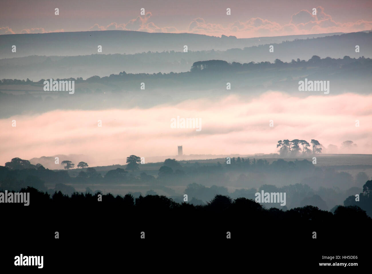 Bands of early morning mist produce a layered landscape with trees ...