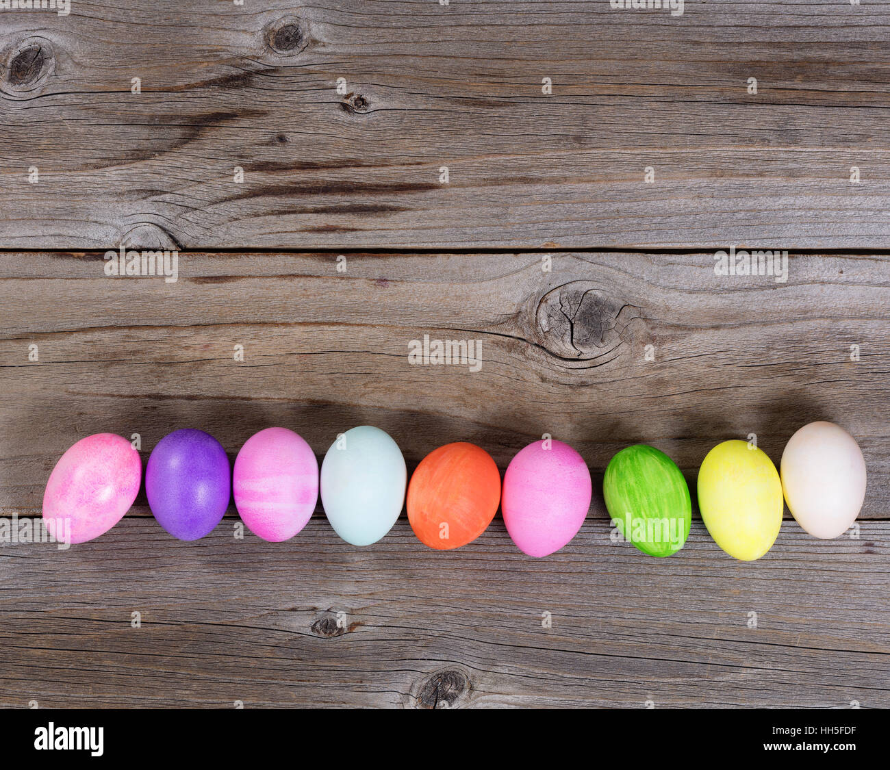 Colorful Easter egg decorations forming lower border on rustic wood ...