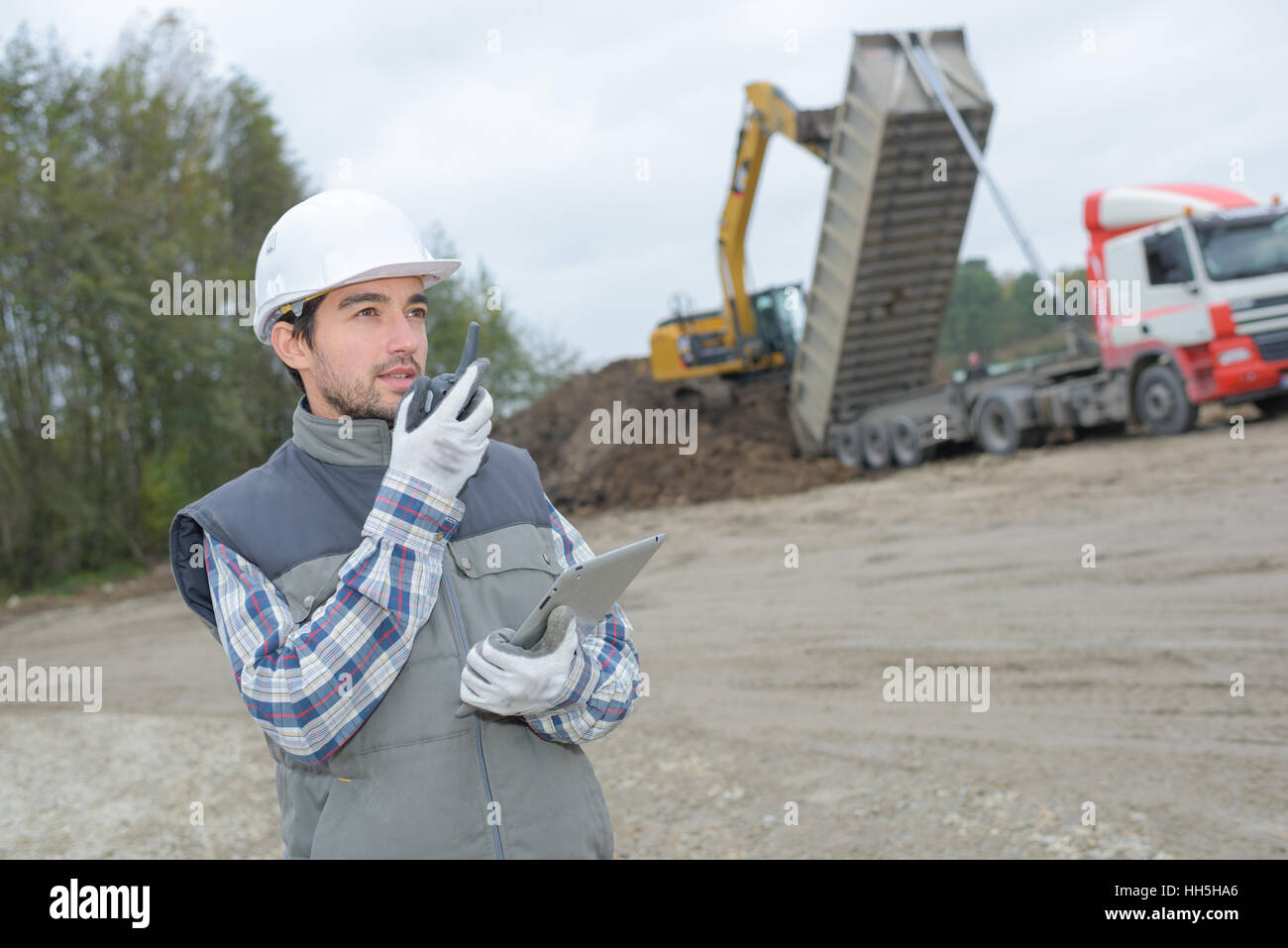 Man on construction site talking into walkie talkie Stock Photo - Alamy