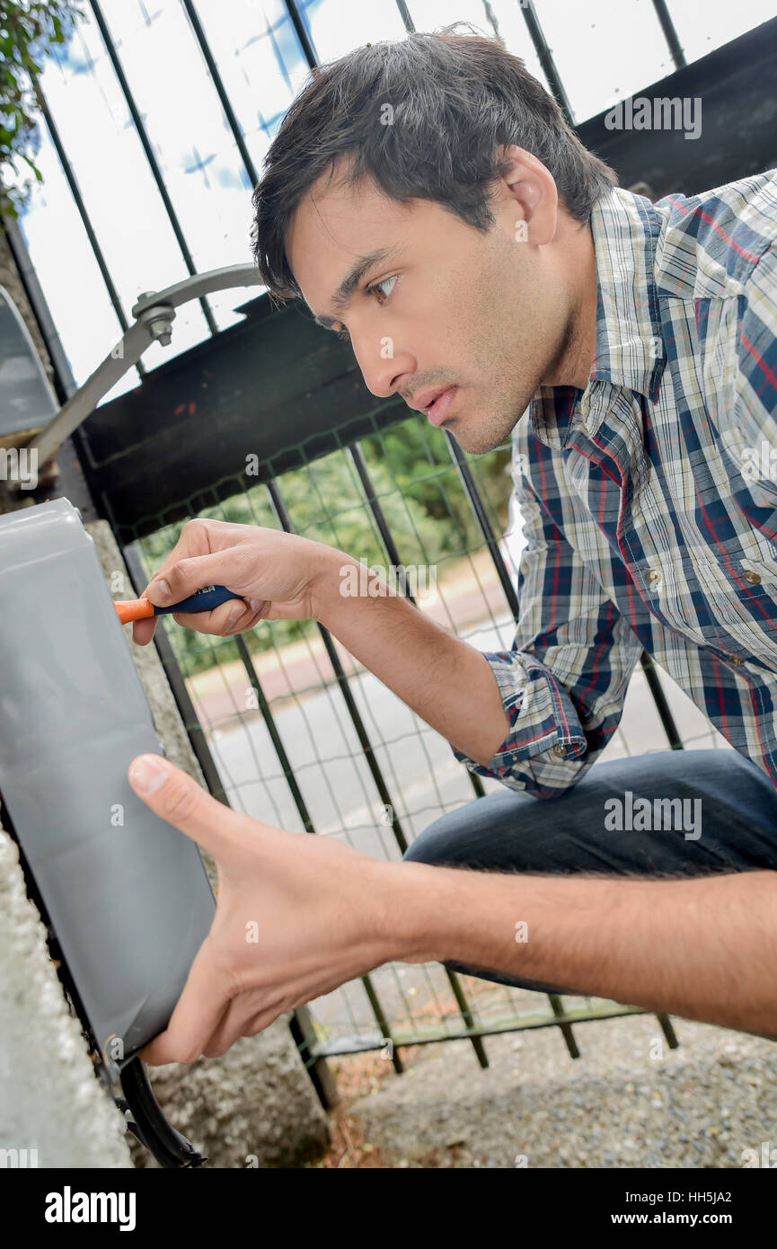 Man fitting box to exterior wall Stock Photo - Alamy