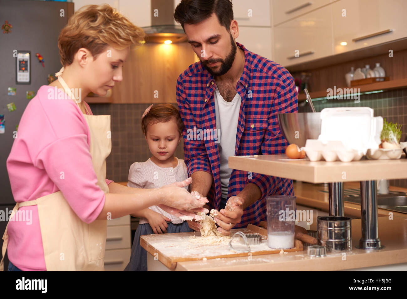 Little girl helping parents at the kitchen Stock Photo - Alamy