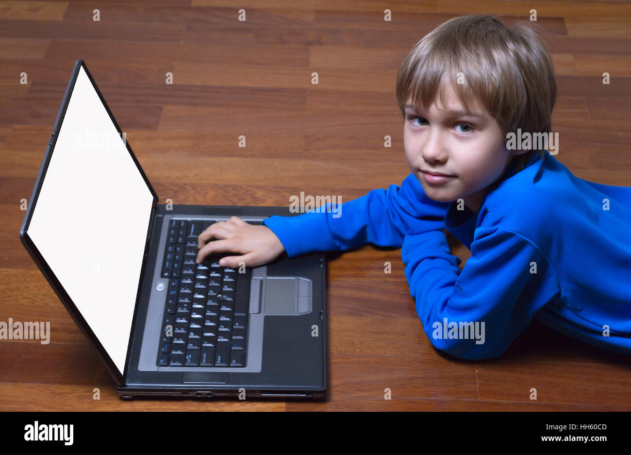 Child using laptop PC lying on wooden floor. Top view. Education ...