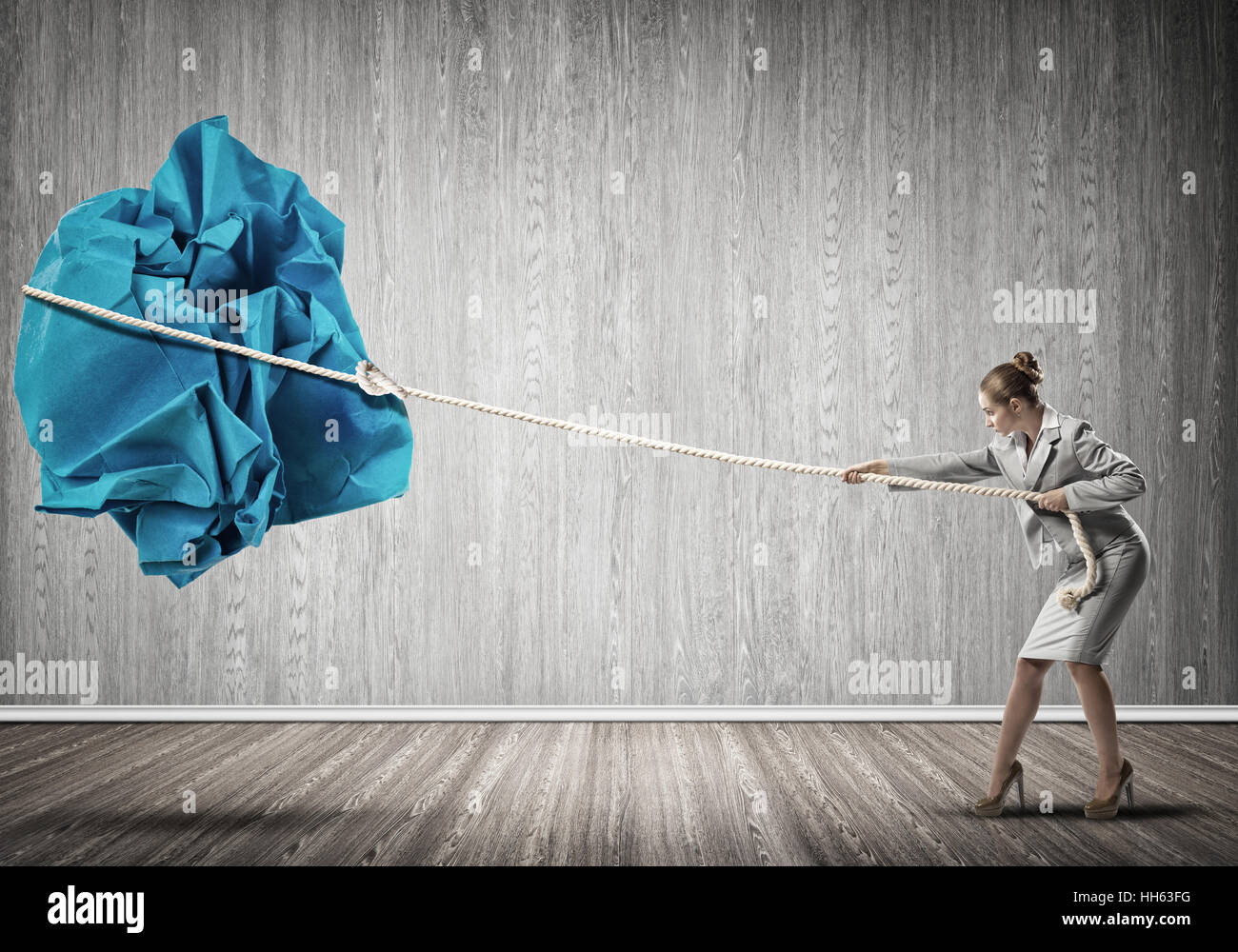 Woman pulling with effort big crumpled ball of paper as creativity sign ...
