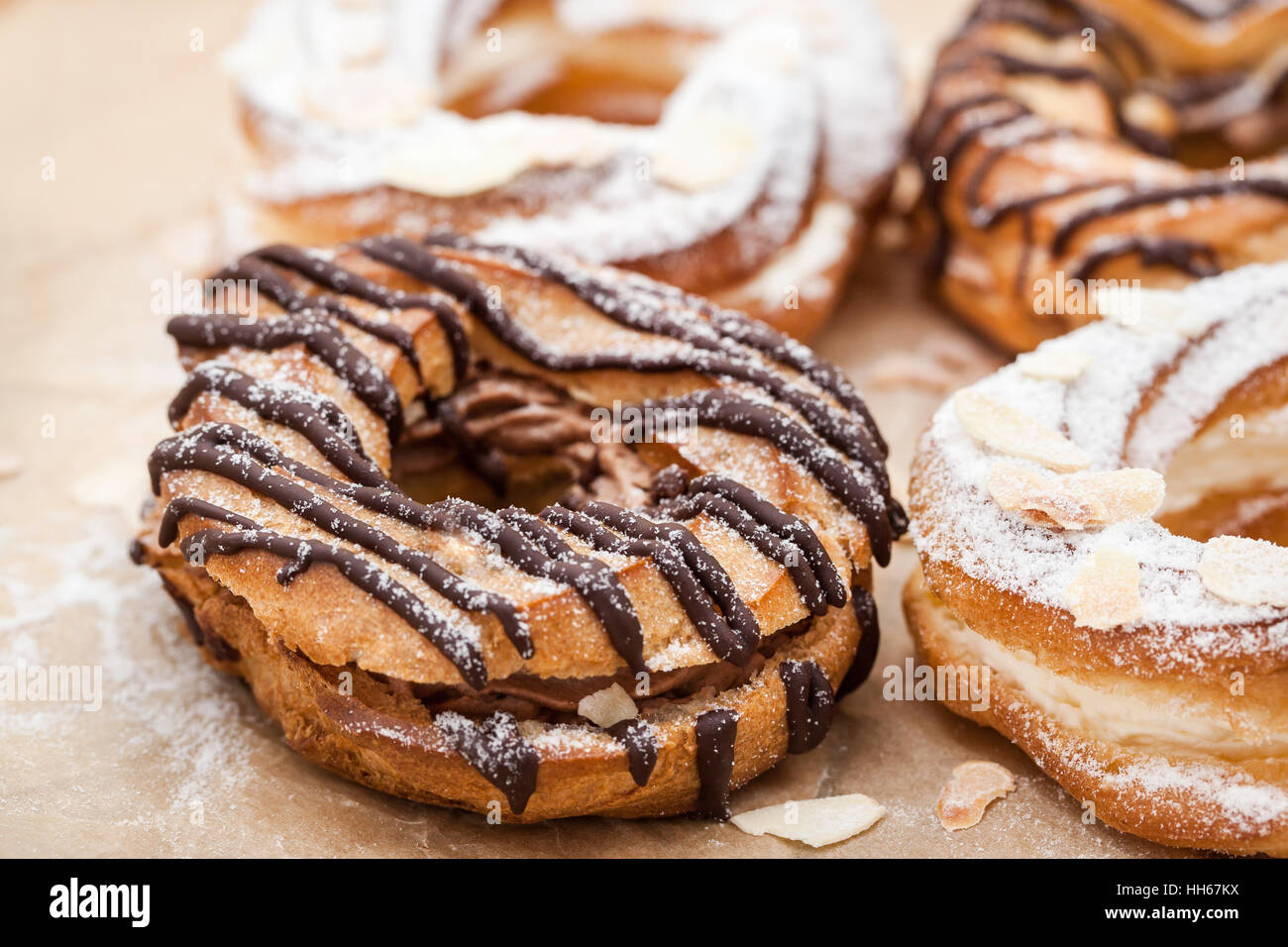 Chocolate and powdered sugar cream puff rings (choux pastry), black and ...
