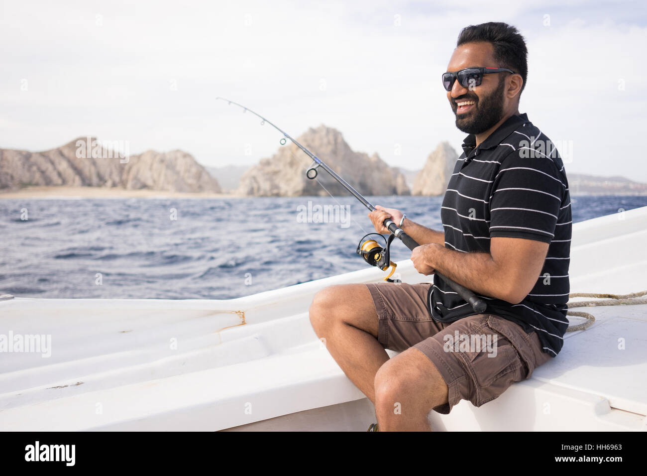 Young East Asian man fishing on open water from the boat. Beautiful ...