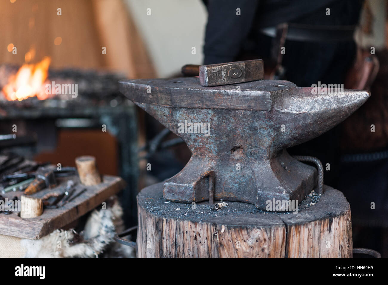 Blacksmith at the workshop. Working metal with hammer and tools on the ...