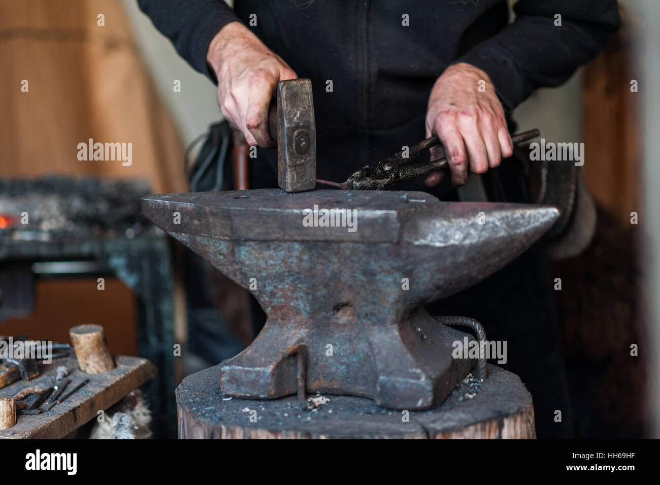 Blacksmith at the workshop. Working metal with hammer and tools on the ...