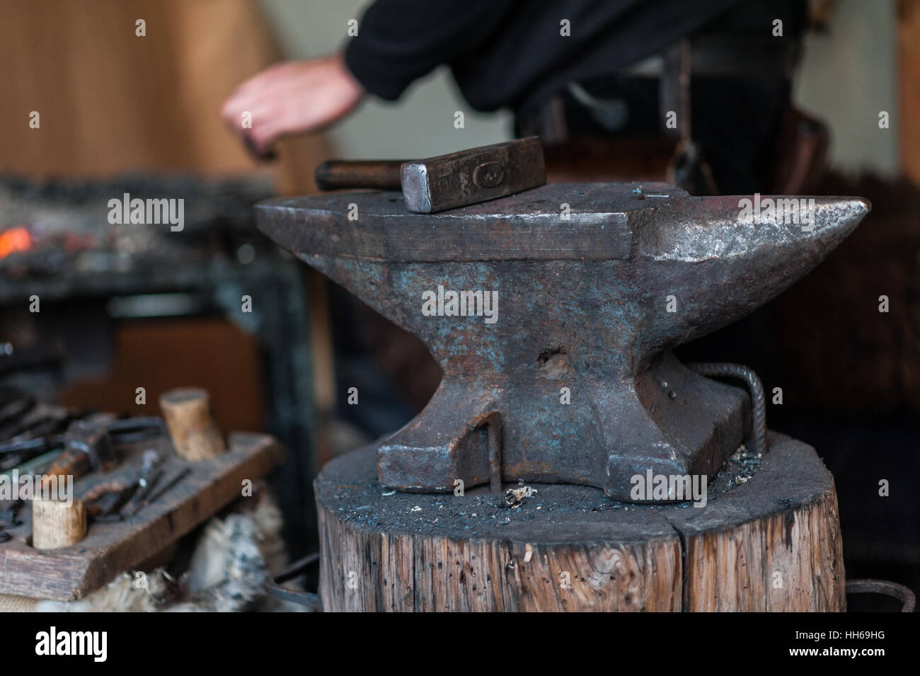 Blacksmith at the workshop. Working metal with hammer and tools on the ...
