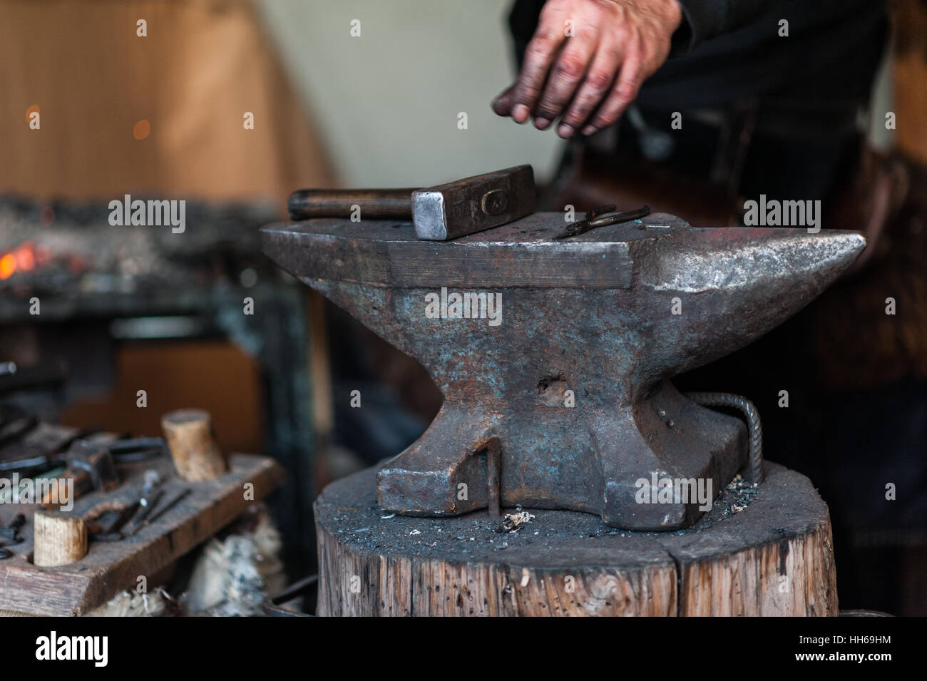 Blacksmith at the workshop. Working metal with hammer and tools on the ...