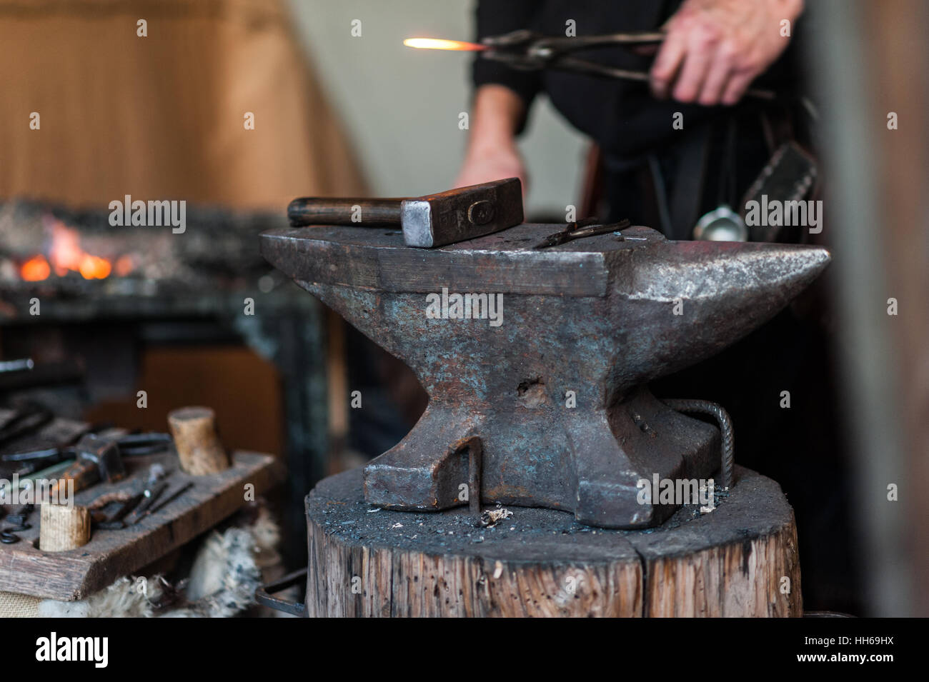Blacksmith at the workshop. Working metal with hammer and tools on the ...