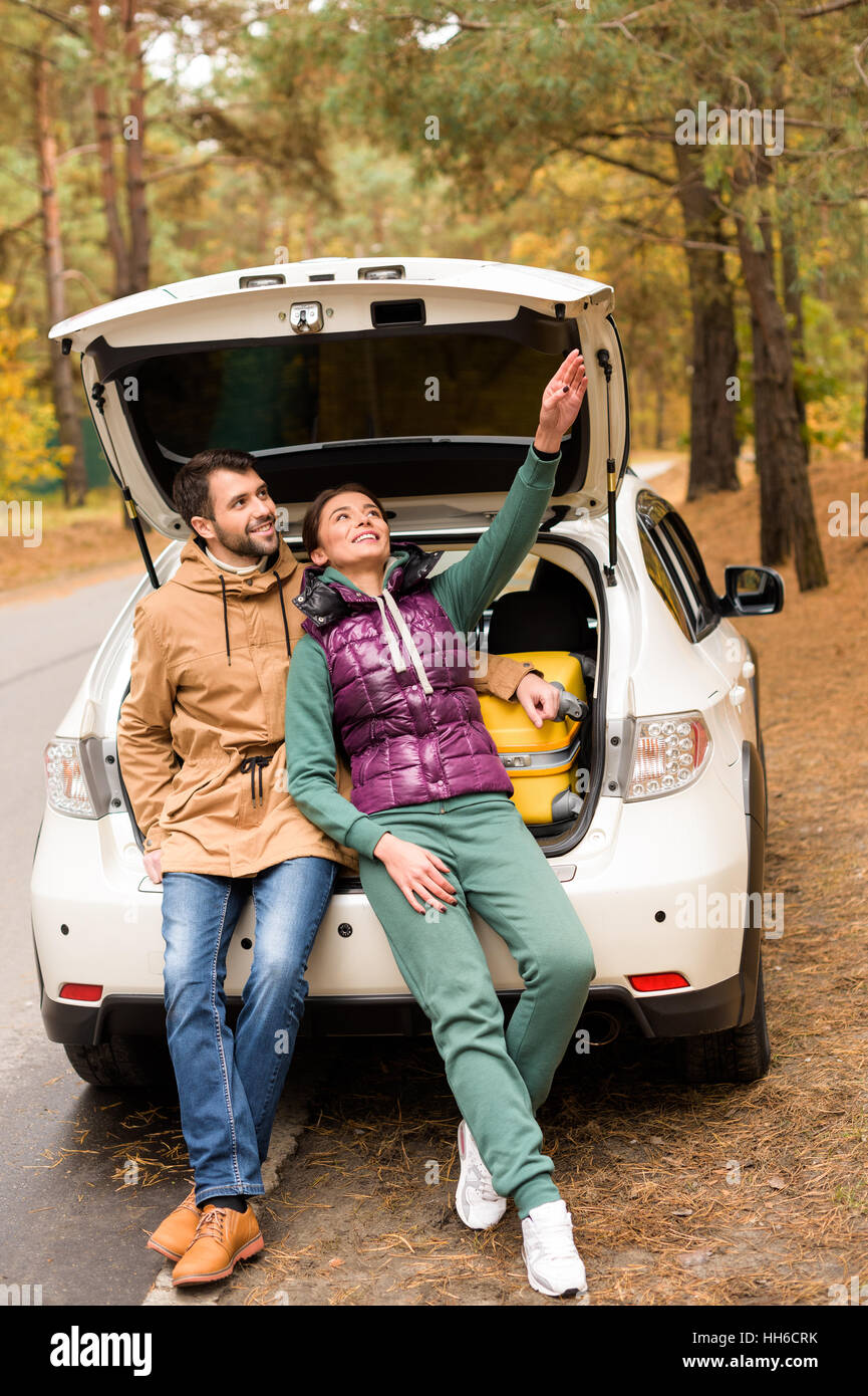 Smiling young couple sitting in open car trunk in autumn forest Stock ...
