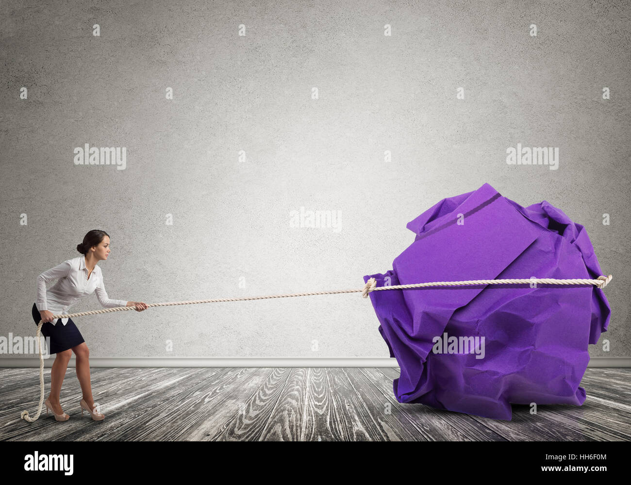 Woman pulling with effort big crumpled ball of paper as creativity sign ...