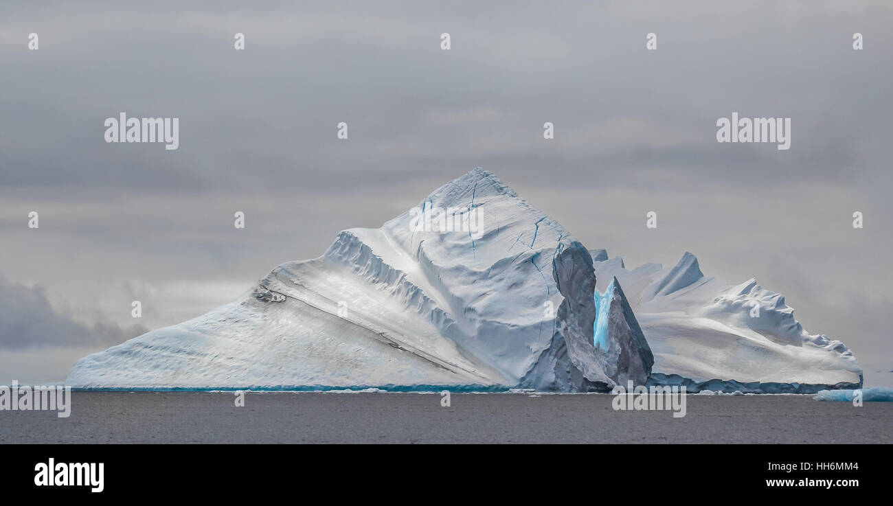 Massive tilted, sculpted iceberg with a giant blue-illuminated crack ...