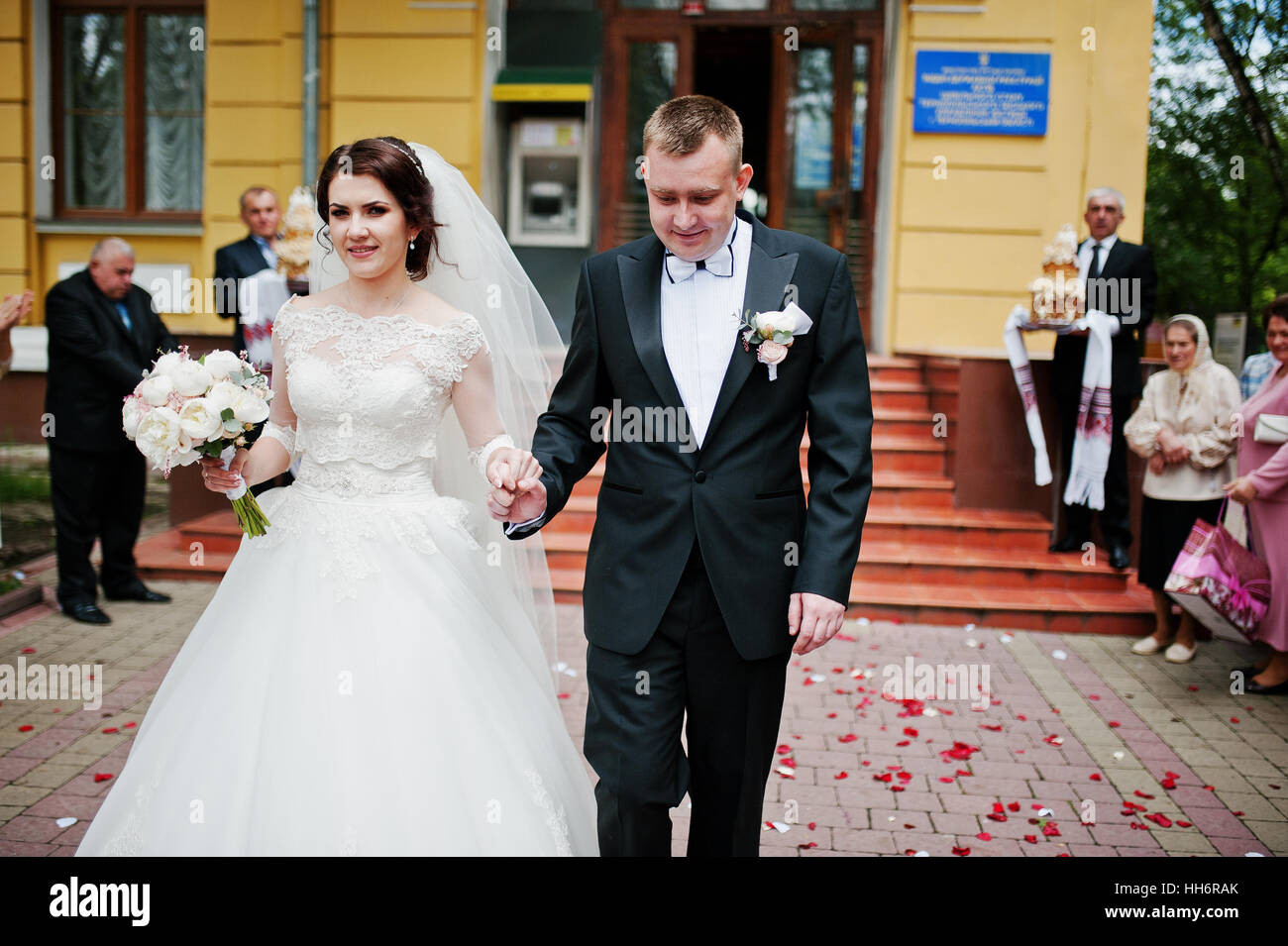 Happy wedding couple walking at path with rose petals after wedding ...