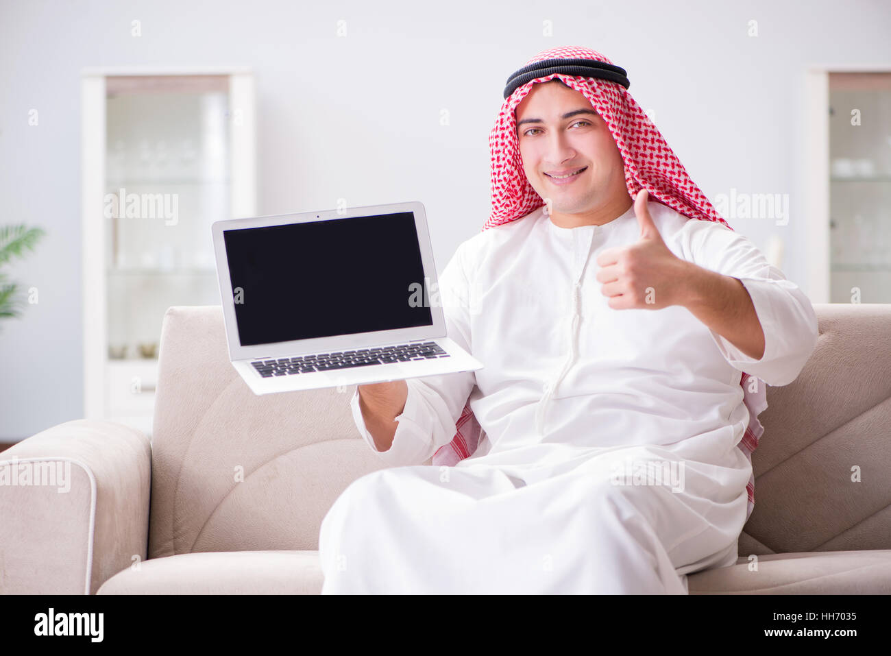 Young arab businessman working with laptop on sofa Stock Photo - Alamy