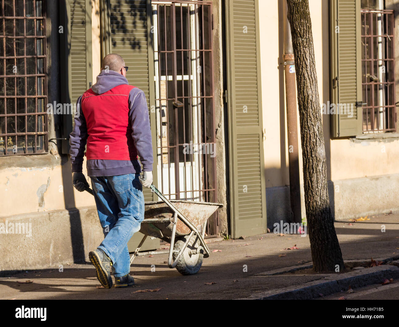 Construction worker pushing a wheelbarrow on the street Stock Photo - Alamy