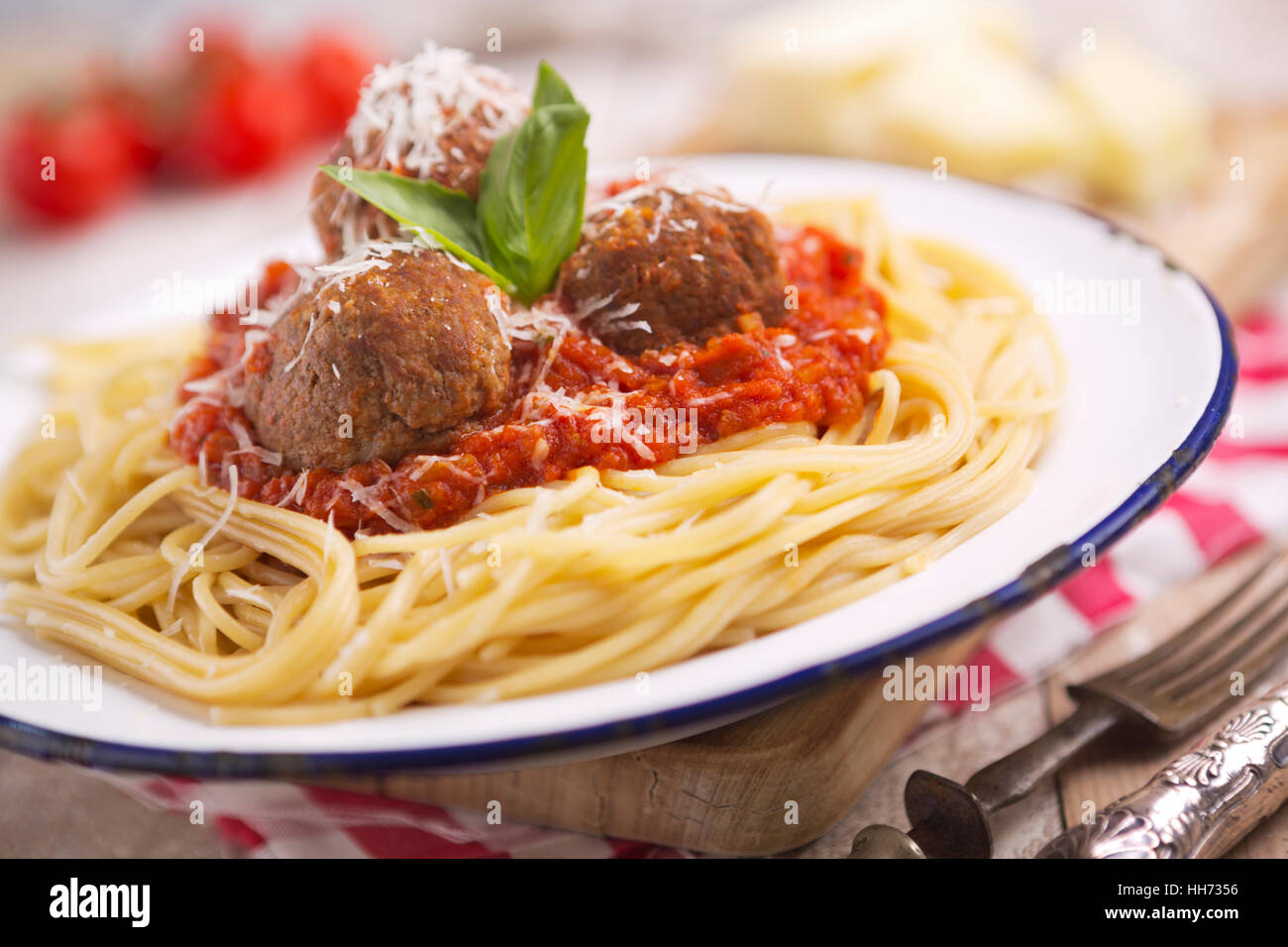A plate with spaghetti with meatballs, topped with some grated parmesan ...