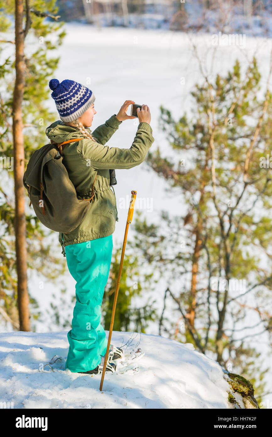Young beautiful woman with snowshoes and mobile phone chill out and ...