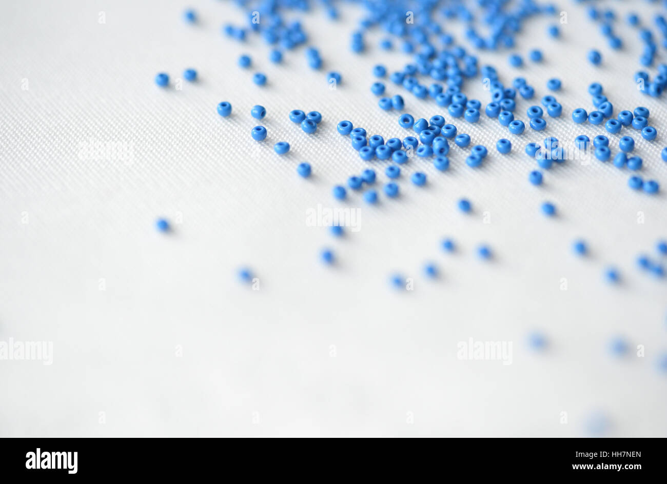 Scattered seed beads of blue color on the textile background Stock ...