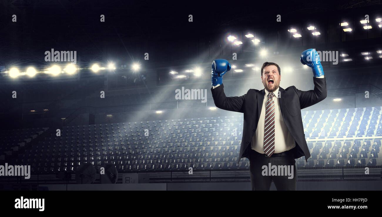 Determined businessman in blue gloves rising hands to celebrate his ...