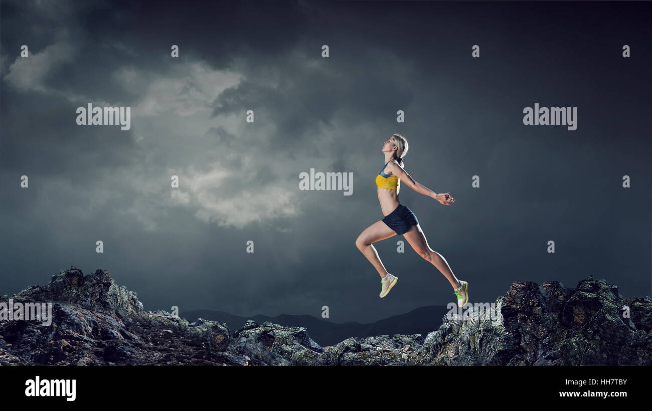 Young woman athlete running fast up the rock mountain Stock Photo - Alamy