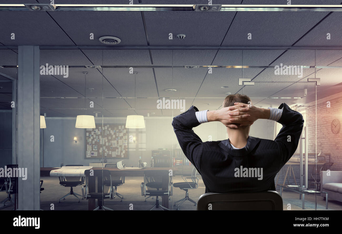 Back view of relaxed businessman sitting on chair with hands on nape ...