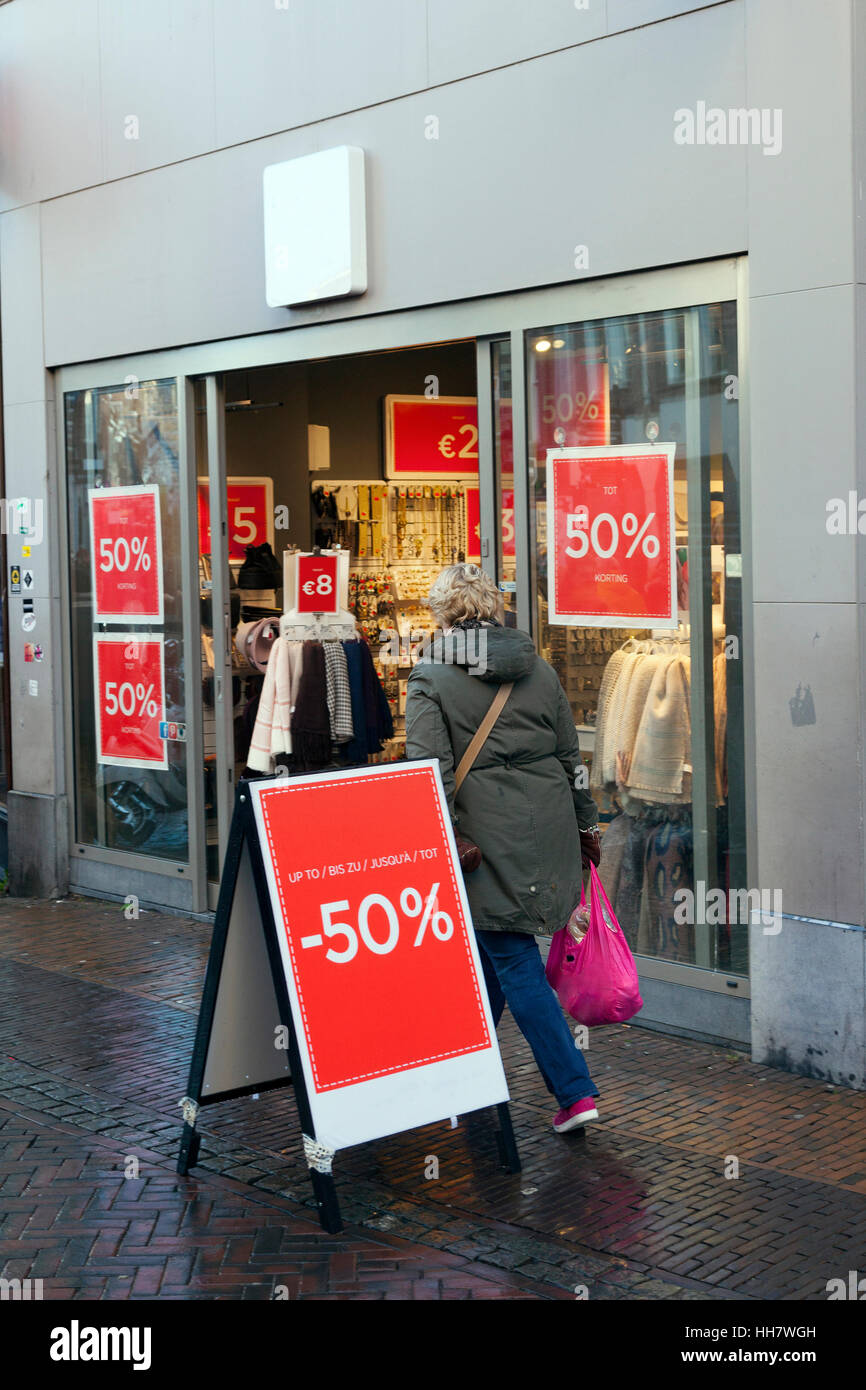 sale signs outside clothing store on rainy street and people with bags ...