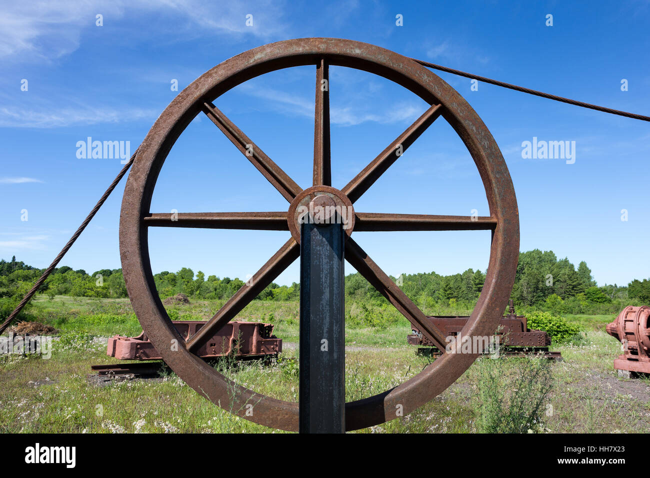 Large rusting industrial wheel with a cable running over the top ...