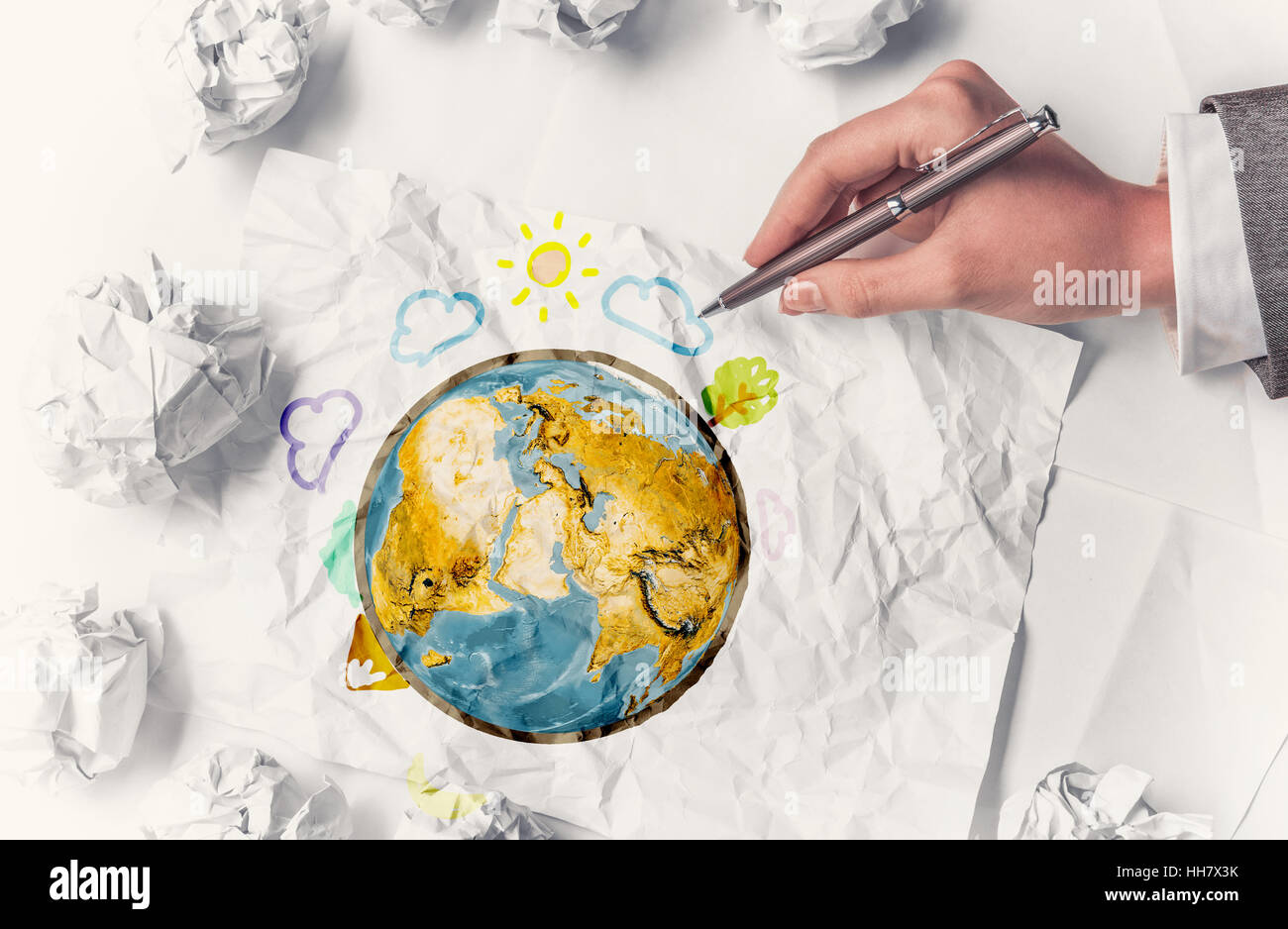Hand of businesswoman drawing Earth planet on crumpled paper. Elements ...