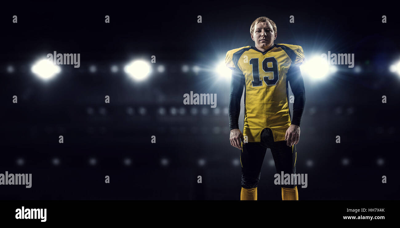 Confident American football player in lights of sport arena. Mixed ...