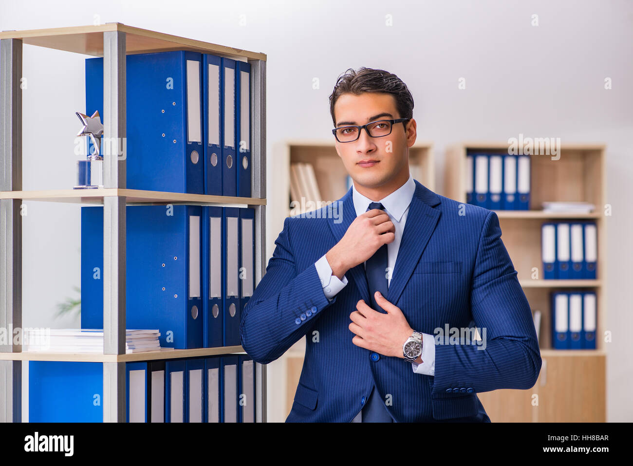 Young man standing next to the shelf with folders Stock Photo - Alamy