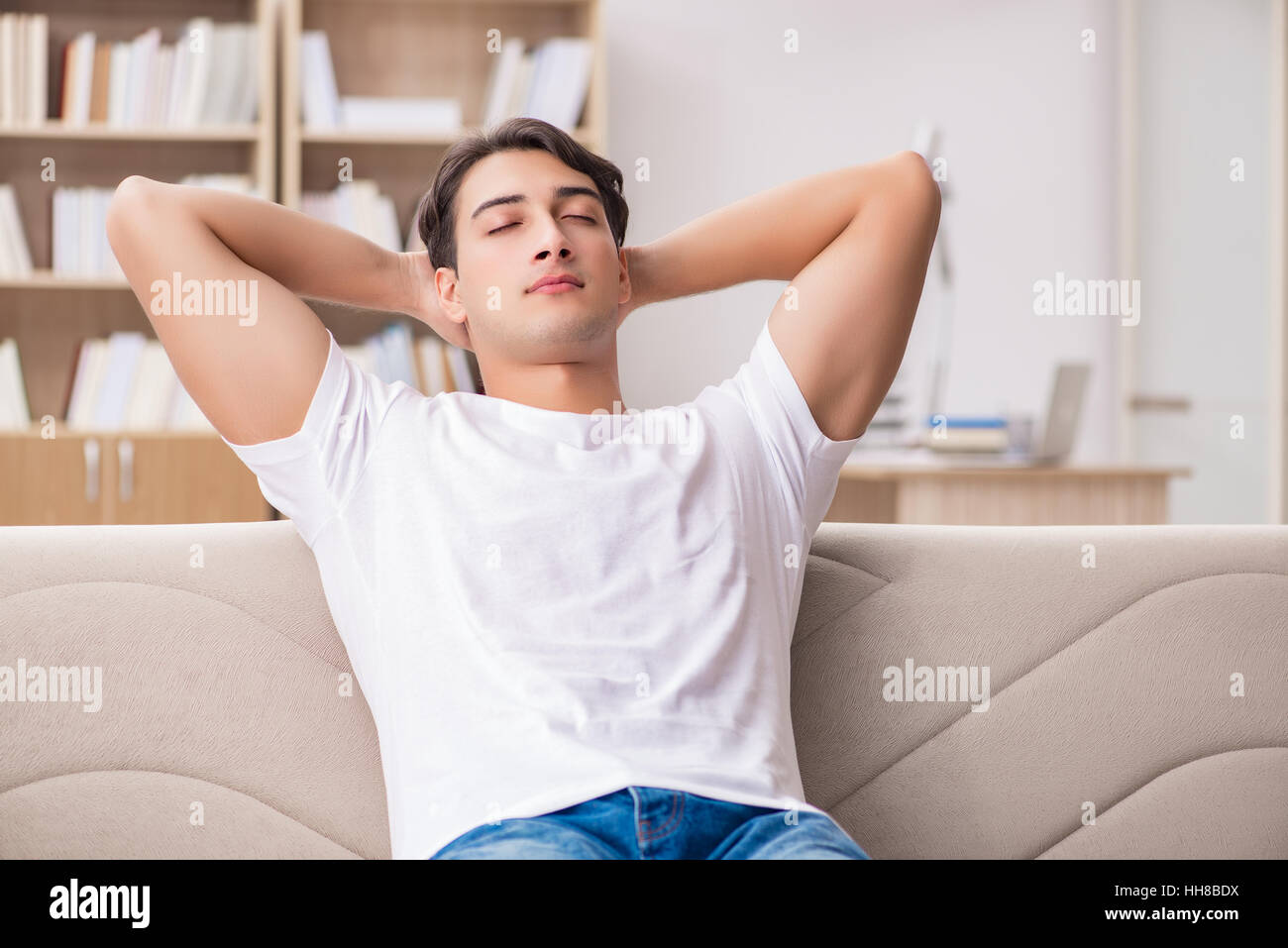 Young man relaxing sitting in couch sofa Stock Photo - Alamy