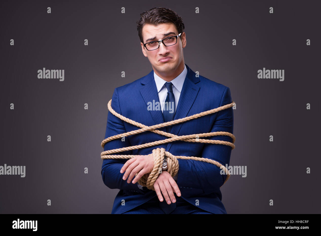 Businessman tied up with rope Stock Photo - Alamy