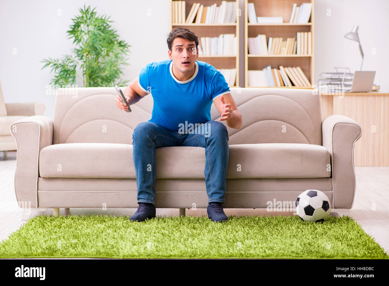 Man watching football at home sitting in couch Stock Photo - Alamy