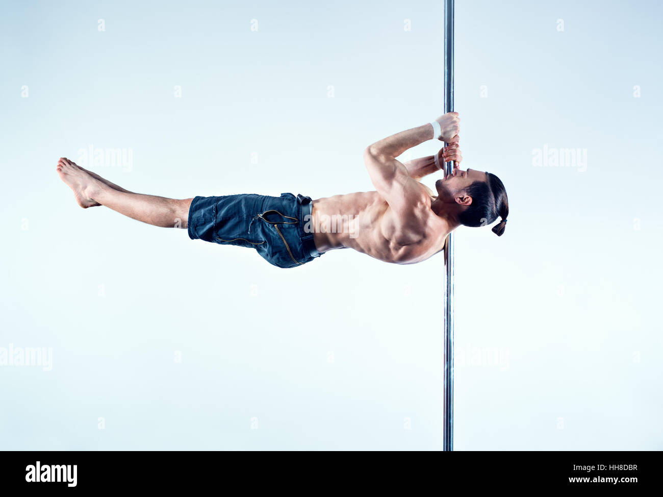 Young strong pole dancing man on blue and white background Stock Photo ...
