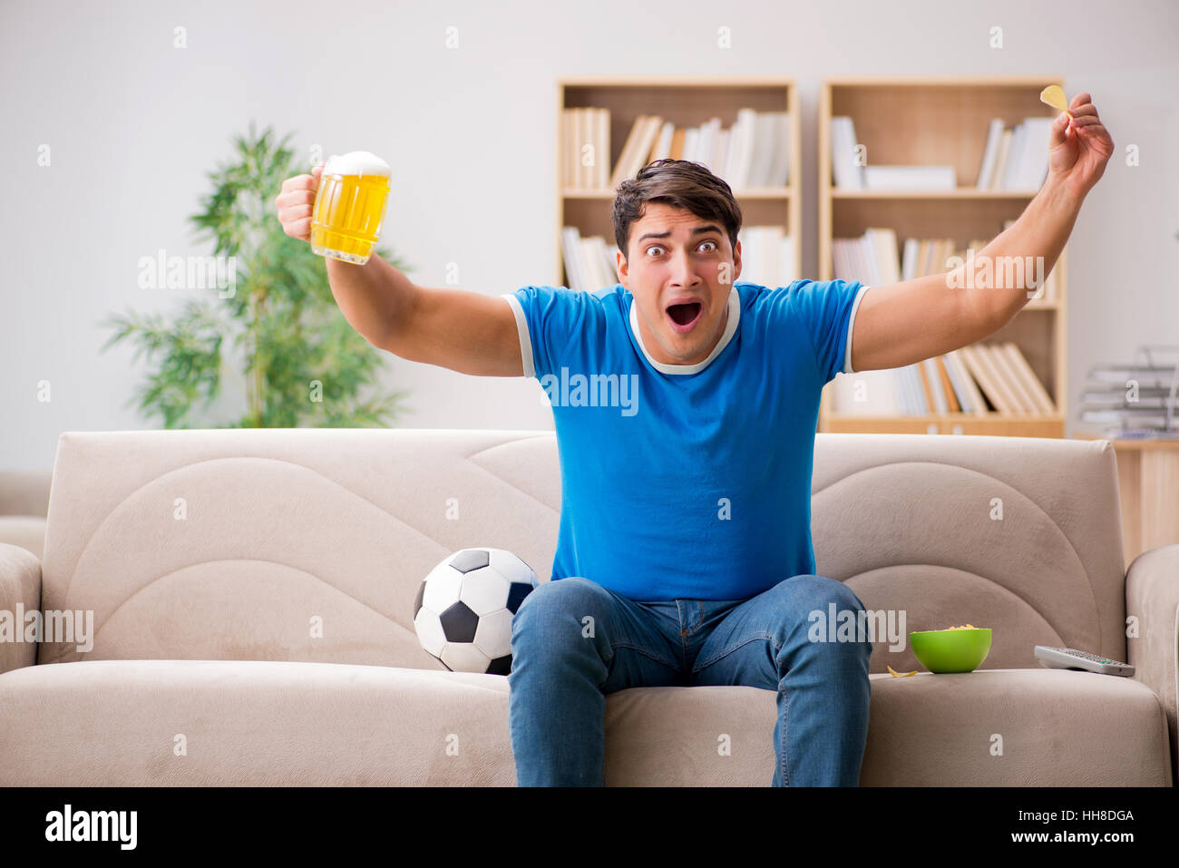 Man watching football at home sitting in couch Stock Photo - Alamy