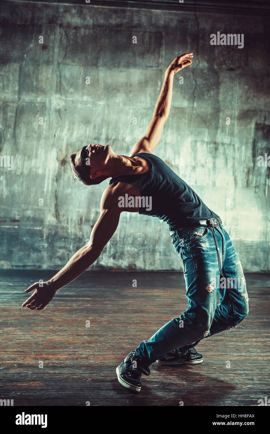 Young man break dancer standing on old wall background Stock Photo - Alamy