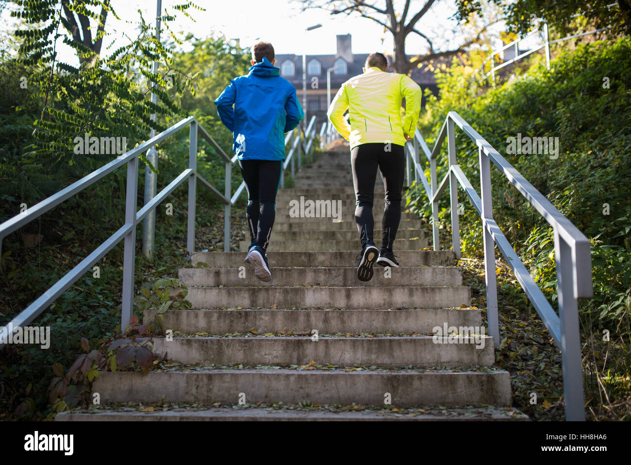 Two athletes running on stairs in sunny autumn, rear view Stock Photo ...